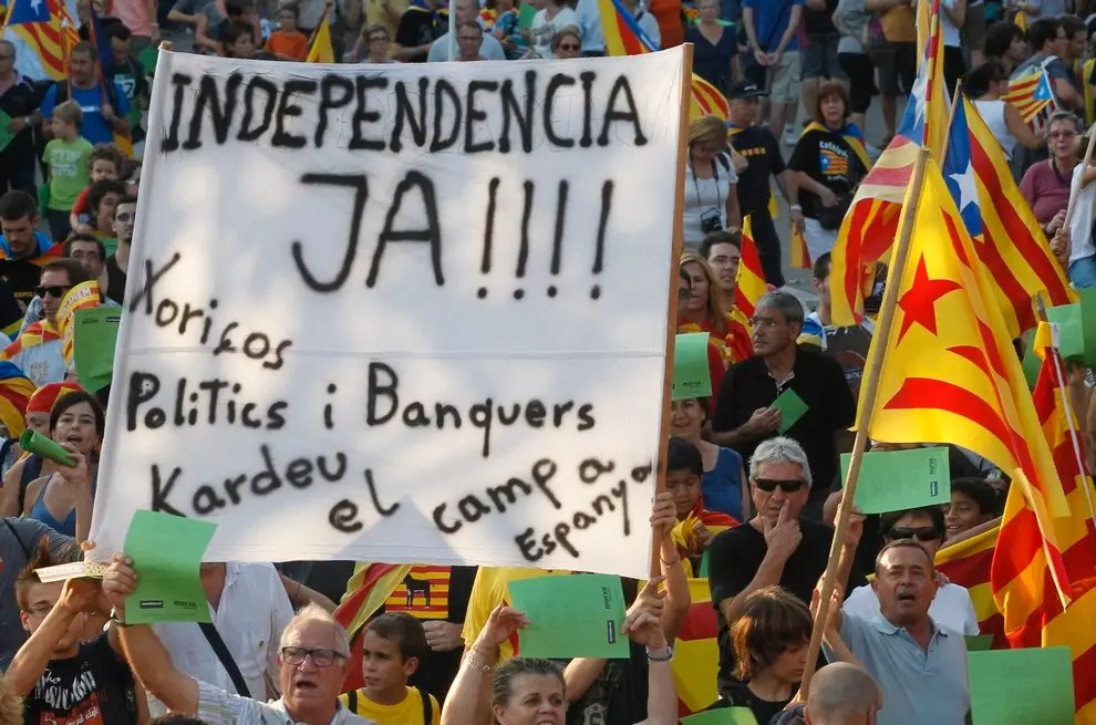 Ndị njem na-ejide ọkọlọtọ na Catalonian Natist flags ka ha na-egosi n'oge Catalan National Day na Barcelona